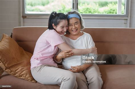 Putri Dewasa Asia Memeluk Ibu Seniornya Di Sofa Di Rumah Wanita Muda