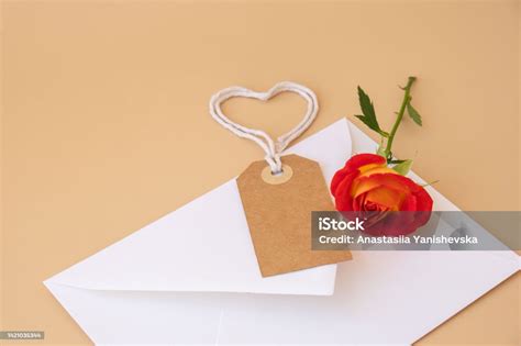 중립 베이지 색 배경에 우편 봉투에 아름다운 빨간 장미 꽃 텍스트 봄 시간 휴일을위한 인사말 카드 심장 모양 복사 공간에 로프가