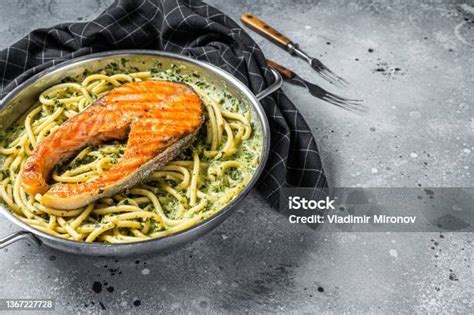 크리미한 시금치 소스와 구운 연어 스테이크를 곁들인 피렌체 파스타 회색 배경 맨 위 보기입니다 복사 공간 건강한 식생활에 대한