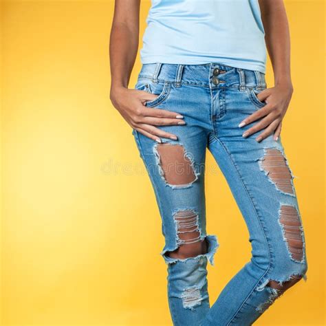 Pernas Femininas Em Jeans Rasgados Num Fundo Laranja Imagem De Stock