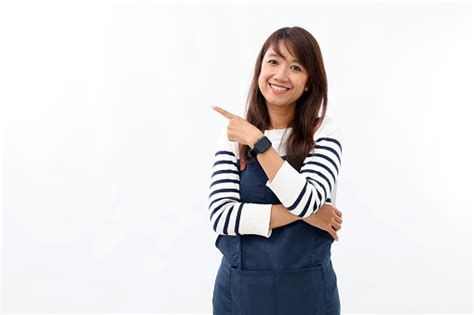 행복 한 아시아 바리 스타가 손가락을 옆으로 가리키고 웃고 푸른 앞치마 유니폼을 입고 흰색 배경에 서 있습니다 공간 복사 35 39세에 대한 스톡 사진 및 기타 이미지