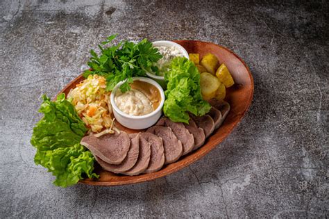 레스토랑 메뉴에서 요리를 제공합니다 회색 돌 테이블 맛있는 애피타이저에 접시에 피클 양배추 소스 허브를 곁들인 얇게 썬 쇠고기