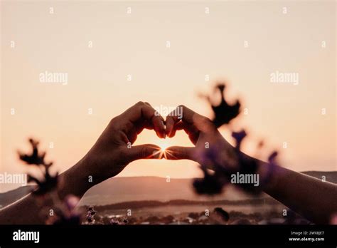 Woman Creates Form A Heart Shape With Hands At Sunset Conveying Serene