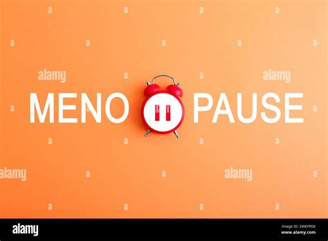 menopause word and alarm clock with pause symbol on orange background