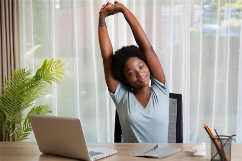 A Woman Stretches At Her Home Desk After Finishing A Task She Looks