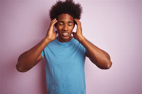 아프리카계 미국인 남자 와 아프리카 계 미국인 남자 Afro 머리 를 입고 푸른 티셔츠 위에 서 고립 된 분홍색 배경 에 손에 머리에 통증 때문에 스트레스 편두통을 앓고