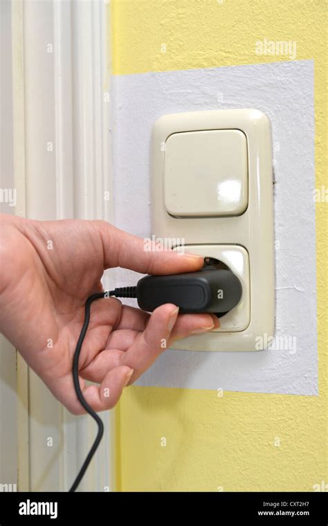 Woman Plugging A Power Adapter Into An Electrical Outlet Stock Photo Alamy