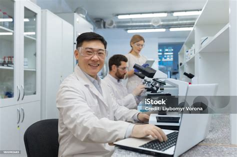 아시아 실험실 기술자의 초상화 실험실 연구에서 일하는 사람들의 팀 그룹과 함께 남자 흰 코트와 고글을 쓴 현미경을 가진 남자가