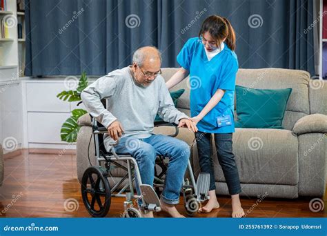 Asian Nurse Assisting Helping Senior Man Patient Get Up From Wheelchair
