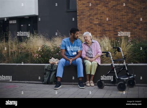Happy Senior Woman Sitting And Talking With Medical Assistant In Front