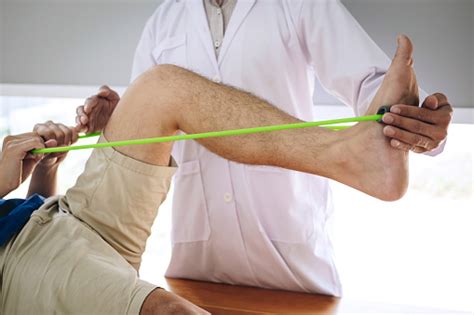 병원에서 침대에 그의 다리를 스트레칭에 치료를 제공 하면서 남성 환자를 돕는 의사 물리 치료사 Kinesiotherapy에 대한 스톡 사진 및 기타 이미지 Istock