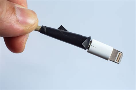 여자의 손 보유 손상 된 흰색 마이크로 Usb 플러그 또는 오래 된 스마트폰 충전기 케이블 흰색 아크릴 테이블 배경에 깨진 닫기