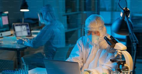 과학 연구 중 책상 옆에 앉아 노트북 키보드에 타이핑하는 보호 작업복을 입은 젊은 진지한 여성 바이러스학자 사진 Unsplash의 실내 이미지