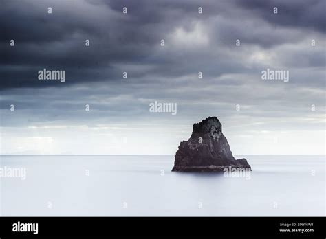 A Dramatic Sky Hangs Over The Tranquil Sea Stack Inspiring Peace And Awe At The Beauty Of