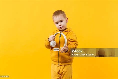 작은 아이가 소년 34 년 된 헤드폰에 노란색 옷을 입고 오렌지 벽 배경 어린이 스튜디오 초상화에 고립 사람들이 진심으 감정