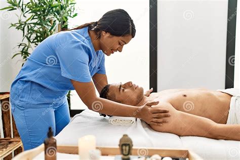 Young Latin Massage Therapist Woman Giving Relaxing Treatment On Man