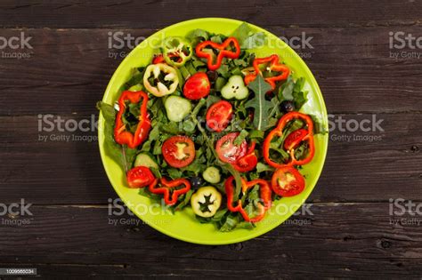 Tamata 오이 양상추 양파와 Arugula 나무 테이블에의 신선한 야채와 야채 샐러드 유리 그릇에 녹색 신선한 야채와 함께
