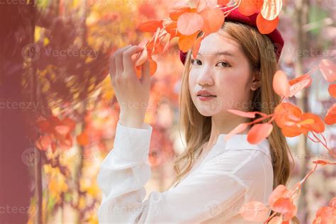 Asian Woman Who Wears White Shirt And Red Cap Stands In Red Orange