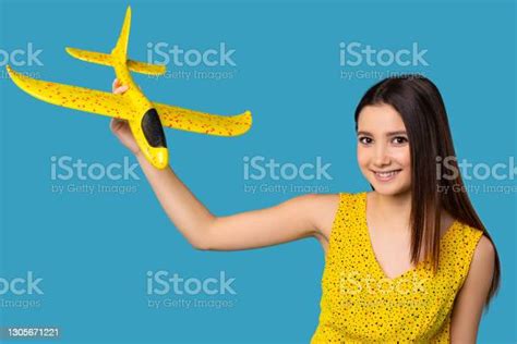 고립된 파란색 배경 위에 조명색 비행기 장난감을 들고 있는 젊은 사업가가 이빨을 보여주는 자신감 넘치는 미소에 만족합니다 항공기 모델을 검사하는 백인 여성 파트너 개념에