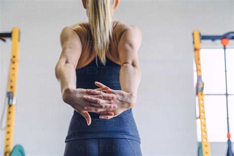 Rear View Of Woman Stretching Hands Behind Back While Exercising In Gym