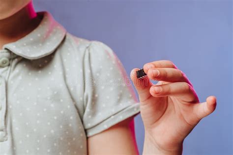 A Girl Holds In Her Hand And Examines A Small Black Chip Stock Image
