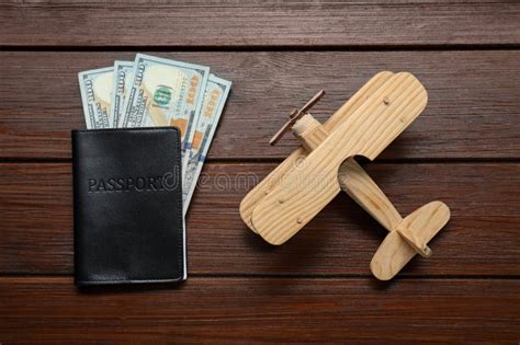Dollars Passport And Model Of Plane On Wooden Table Flat Lay