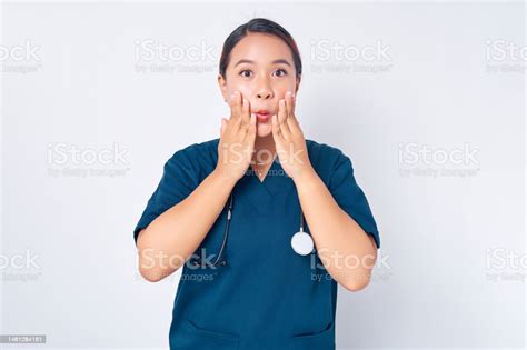 청진기와 함께 파란색 유니폼을 입은 놀란 젊은 아시아 여성 간호사는 카메라를 말없이 쳐다보고 놀라서 헐떡이며 발표를 듣고 흰색