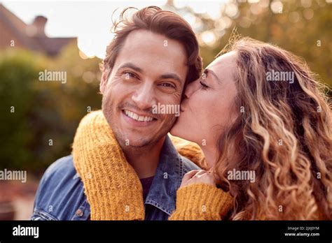 Portrait Of Happy Loving Couple With Woman Giving Man Kiss On The Cheek