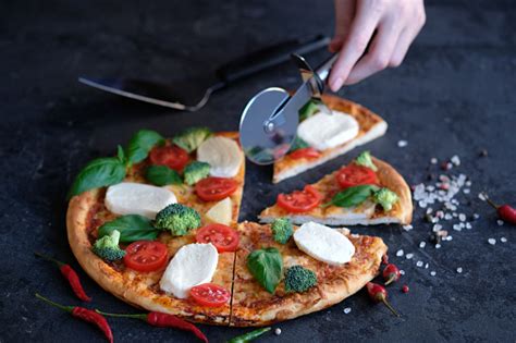 모 짜 렐 라 치즈 토마토 브로콜리 향신료 및 신선한 바 질을 블랙 스톤 배경에 얇게 썰어 놓은 피자 이탈리아 피자입니다 피자 나이프와 피자를 절단 0명에 대한 스톡 사진