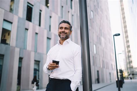 시내의 도시 환경에서 웃고있는 현대 휴대 전화를 가진 행복한 전문 직원 금융 지구에서 비즈니스 라이프 스타일을 즐기는 스마트 폰 장치를 들고 성공적인 기업가 35 39세에