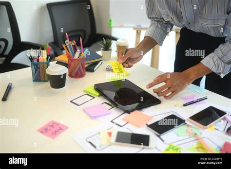 Team Of Creatives Collaborating On A Ux Ui Project At Workspace Filled With Flowcharts And