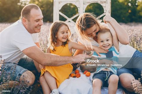 어머니 아버지와 여동생이 일몰에 꽃밭에서 동생을 간질이는 동안 야외에서 즐거운 시간을 보내는 사랑스러운 큰 가족의 초상화 가족에