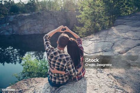 좋은 나무에 빛나는 아침 두 사람의 사랑 수용 손으로 하트 모양을 만드는 협곡 돌 바위 위에 앉아 캐주얼 입고 후면 다시 높은 각도 보기 모양에 대한 스톡 사진 및 기타