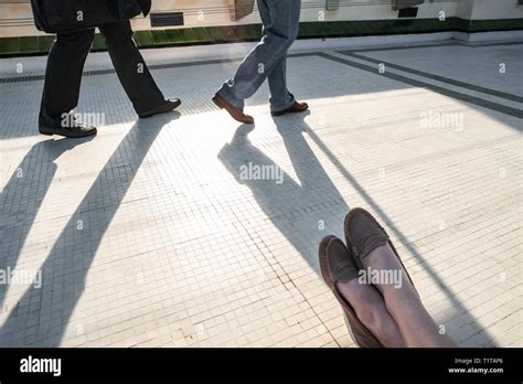 A Woman Relaxes In The Evening Sun While Passers By Cast Long Shadows