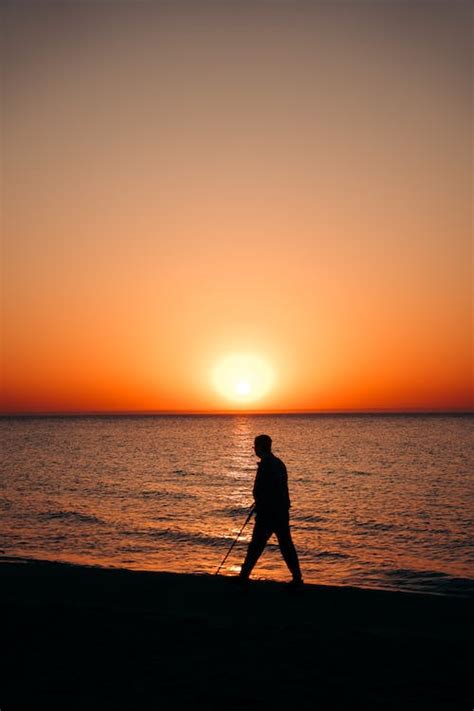 Silueta De Hombre Estar De Pie En Playa Durante Ocaso · Foto De