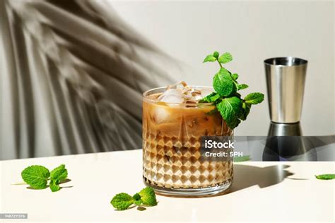 보드카 커피 리큐어 민트 슈납스 베이지색 배경에 크림과 얼음 단단한 빛 그림자 패턴 복사 공간이 있는 민트 화이트 러시아 알코올