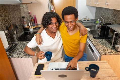 Premium Photo Gay Couple Using Laptop Sitting On The Kitchen Drinking