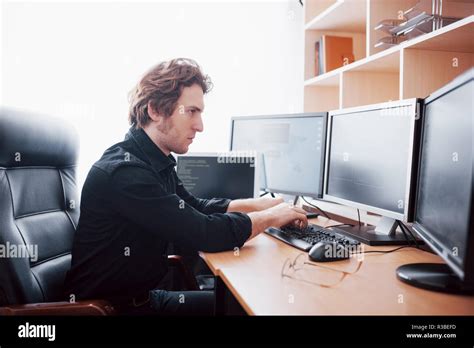 male programmer working on desktop computer with many monitors at