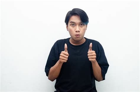 파란 머리를 엿보는 잘생긴 매력적인 아시아 남자는 행복하게 웃고 하얀 배경 위에 고립된 칭찬으로 엄지손가락을 치켜세운다 엄지
