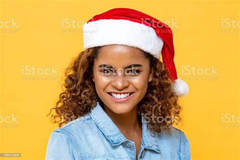 노란 고립 된 배경에 크리스마스 모자를 쓰고 미소 짓는 아프리카 계 미국인 여성의 초상화 25 29세에 대한 스톡 사진 및 기타 이미지 25 29세 경외감 곱슬 머리