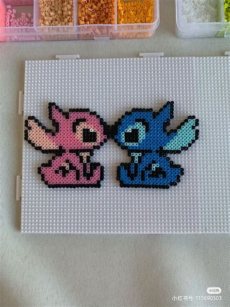 Two Stitched Cartoon Characters Sitting Next To Each Other On A Piece