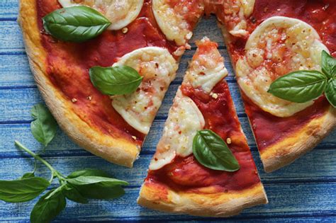 얇게 썬 갓 구운 수제 마르게리타 피자 골든 버팔로 모짜렐라 치즈 서클 풍부한 토마토 마리나라 소스 신선한 바질 잎 토핑 푸른 혀와 그루브 효과 배경 높은 전망 0명에 대한