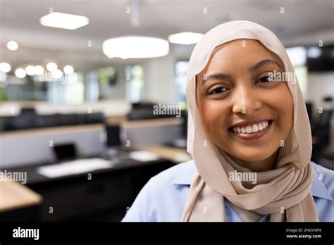 Happy Middle Eastern Businesswoman In Hijab Looking At Camera In Office