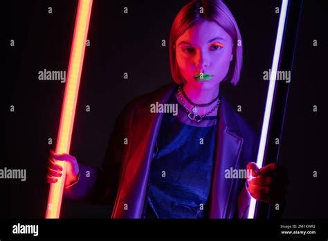 Pretty Woman In Neon Makeup And Leather Jacket Holding Purple