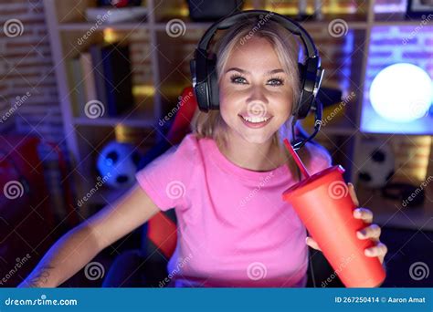 Young Blonde Woman Streamer Playing Video Game Drinking Beverage At