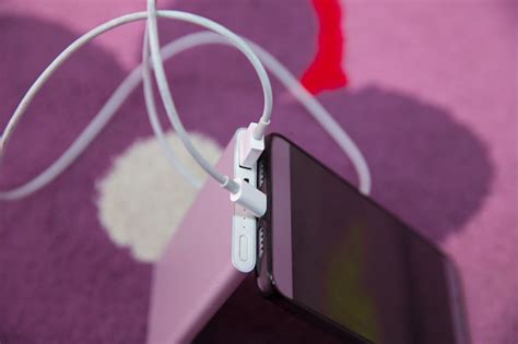 나선형 Usb 케이블을 통해 실버 파워 뱅크와 스마트 폰 충전 분홍색 카펫에 전원 뱅크로 충전하는 스마트 폰 에너지 뱅크로 전화