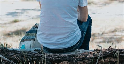 Una Mujer Sentada En Un Tronco En La Playa Foto Imagen De Playa En