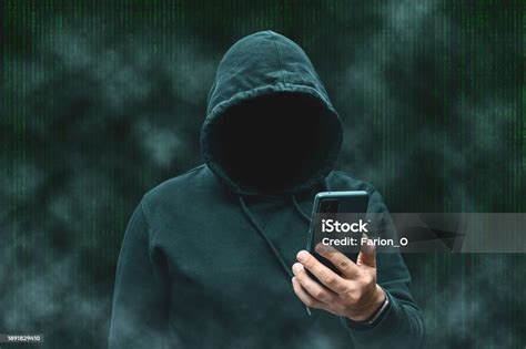 스마트 폰을 들고있는 신비한 얼굴없는 후드를 쓴 익명의 해커 사이버 범죄자 테러리스트의 실루엣 스토커에 대한 스톡 사진 및 기타 이미지 Istock