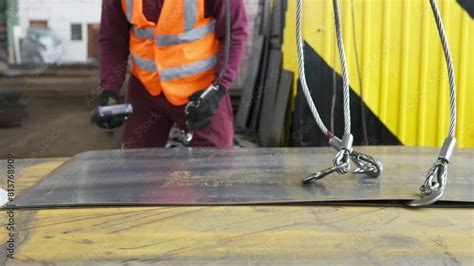 A Worker Moves Large Industrial Metal Parts Using A Remote Controlled