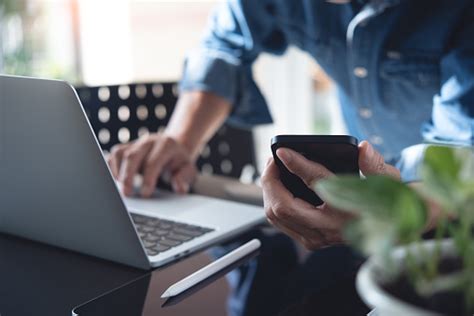 모바일 스마트 폰을 사용하고 흐릿한 배경으로 집에서 나무 테이블에서 노트북 컴퓨터에서 작업하는 아시아 사업가의 클로즈업 검색에 대한 스톡 사진 및 기타 이미지 Istock